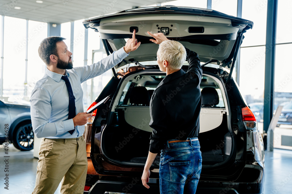 Rear view of blond good looking female customer with a salesman ...