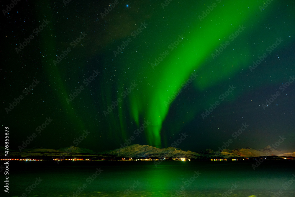 Northern Lights over a Fjord in Norway with the view on a small town ...