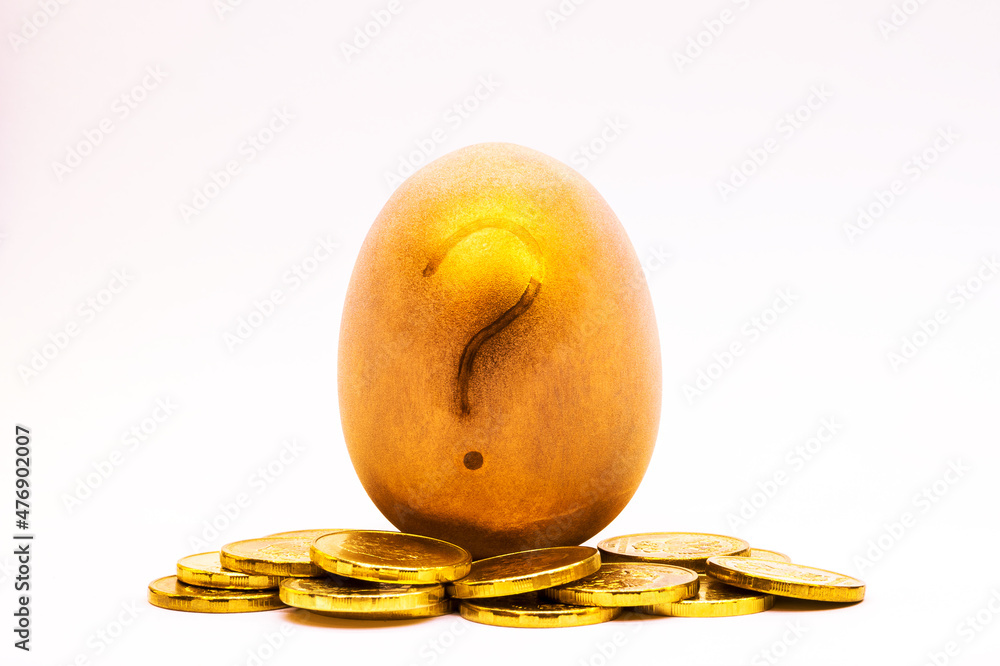 Yellow metal coins and a golden egg with a question mark on a white ...