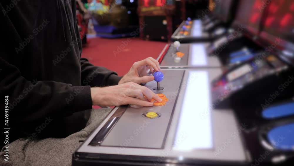 Man hands playing retro arcade machine game and pushing orange buttons ...