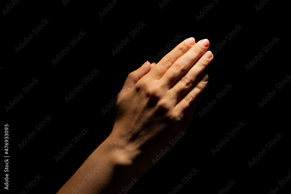 Praying hands on a black background. Light from above. Hands folded in ...