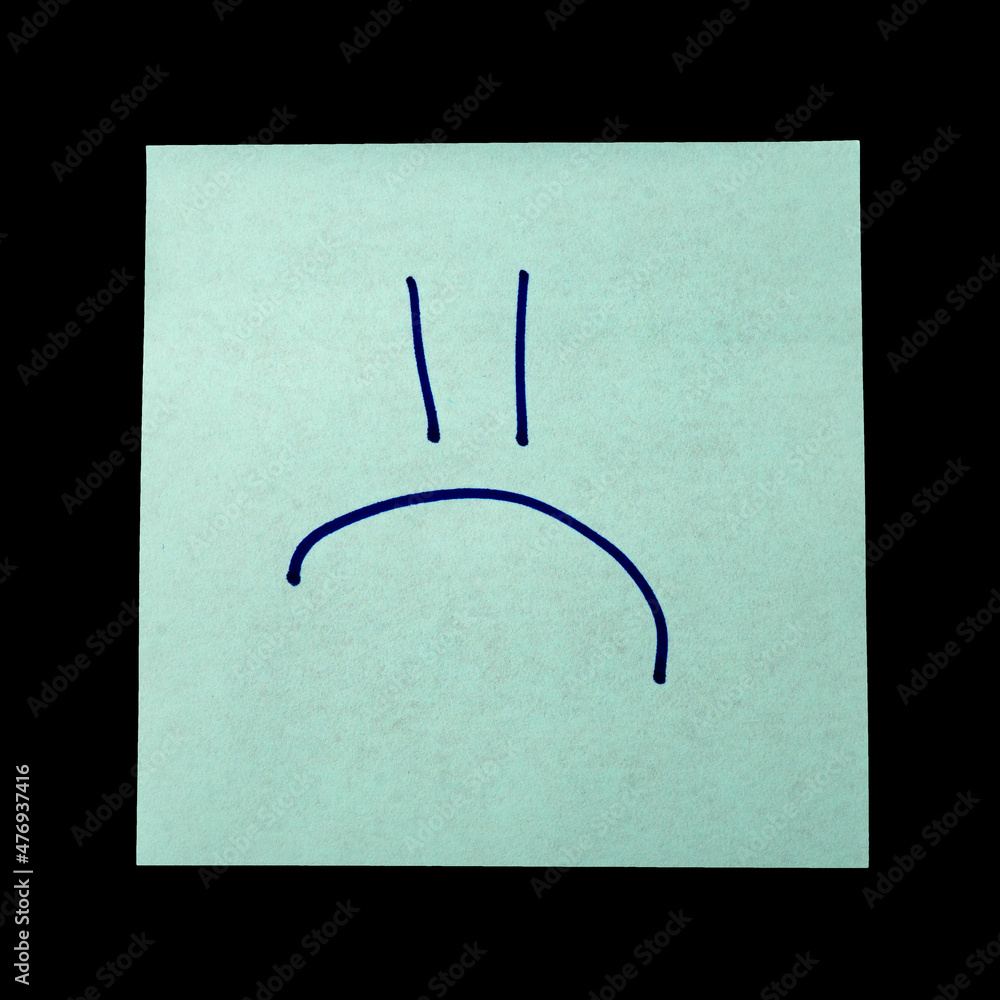 Paper sticker with the image of the symbol of a sad emoticon on dark ...