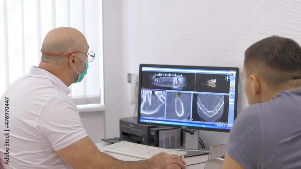 The dentist shows an X-ray of the jaw and teeth to the patient on the ...