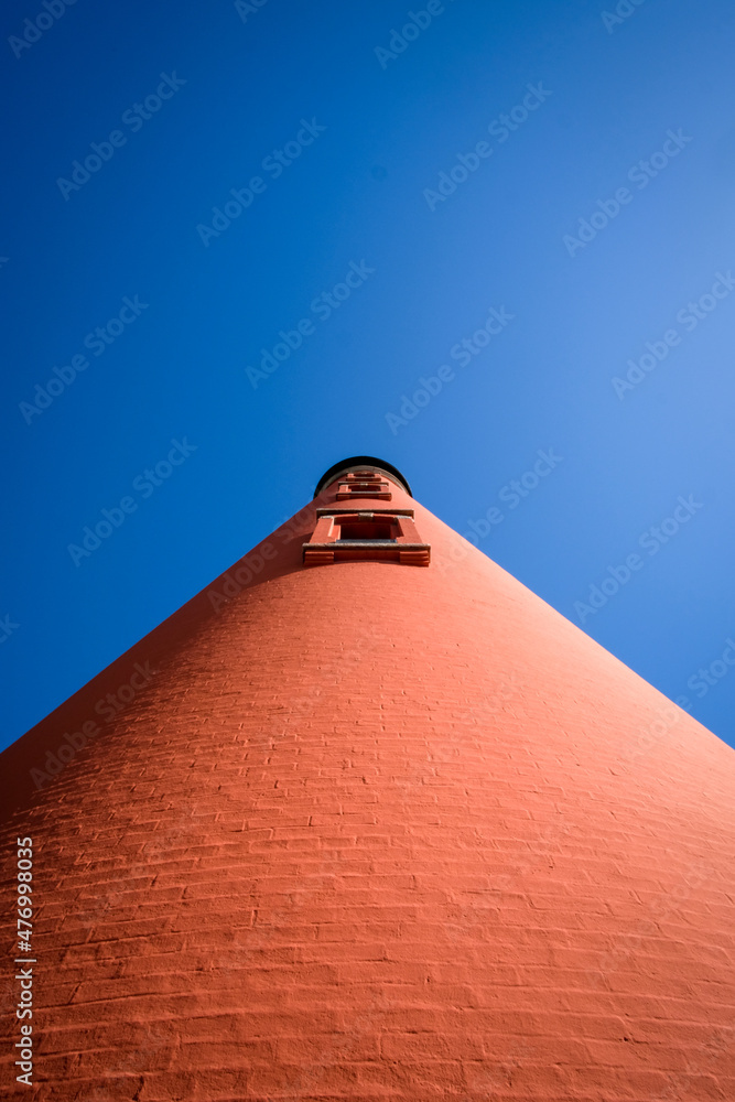 Looking up at a tall lighthouse with clear blue sky and negative space ...