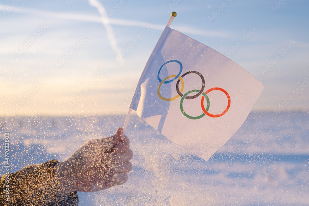 The Olympic flag, small in hand, flutters against the backdrop of snow ...