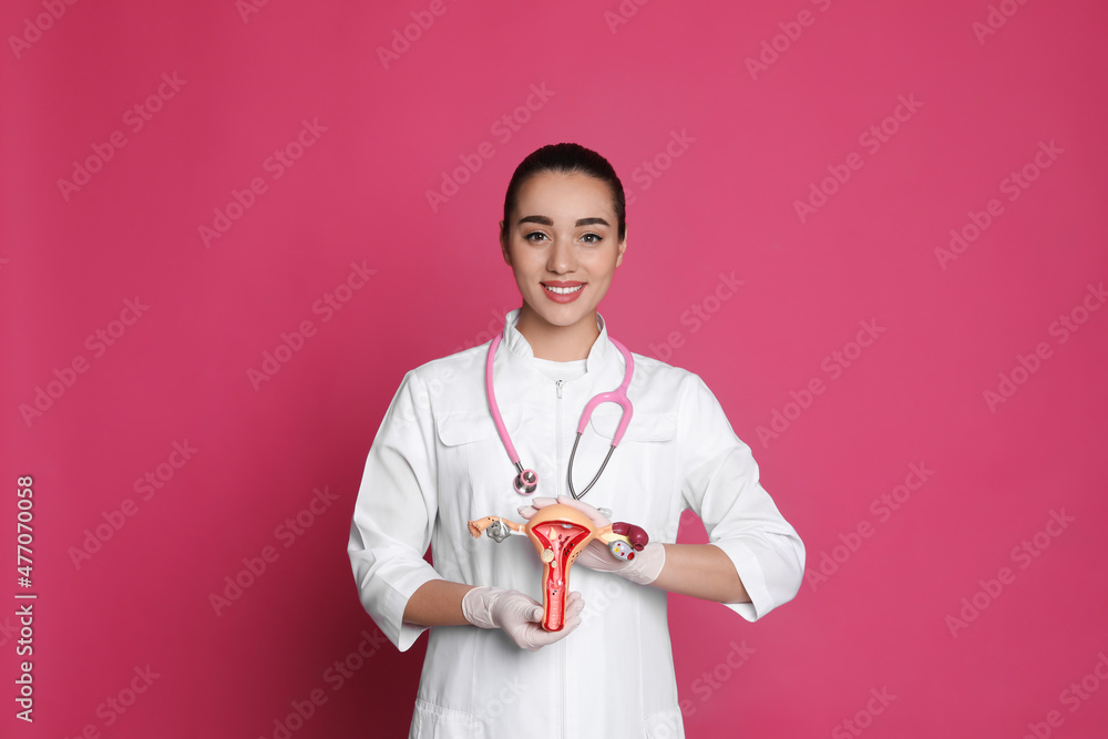 Doctor demonstrating model of female reproductive system on pink ...
