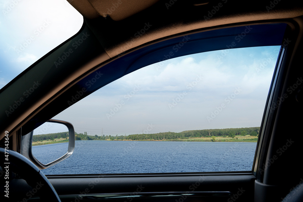 Looking out the passenger side window of a car at the forest Reservoir ...