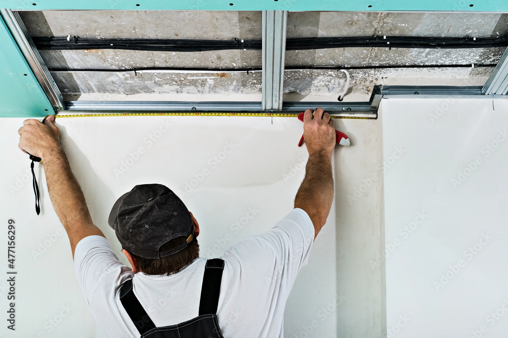 Worker measures the frame before installing the drywall. Installation ...