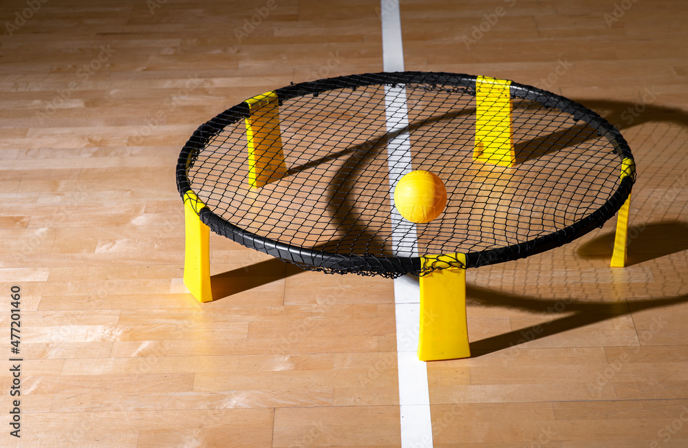 Spike ball game with yellow ball on hardwood court floor. Horizontal ...