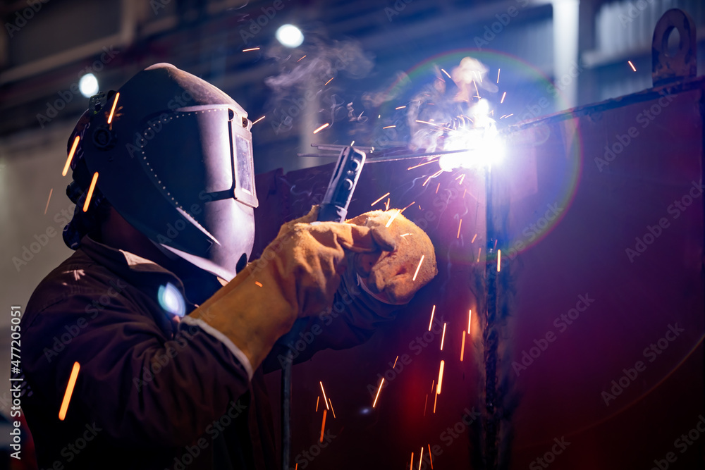 The welder welds metal structures by manual electric arc welding. MMA ...