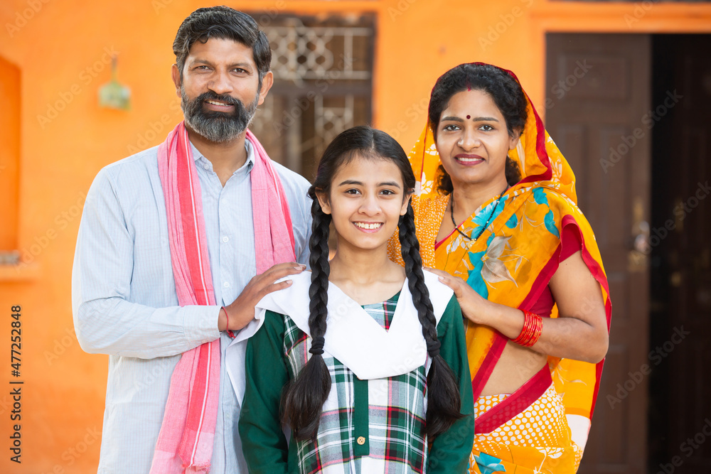 Portrait of happy Indian family standing outside their house in village ...