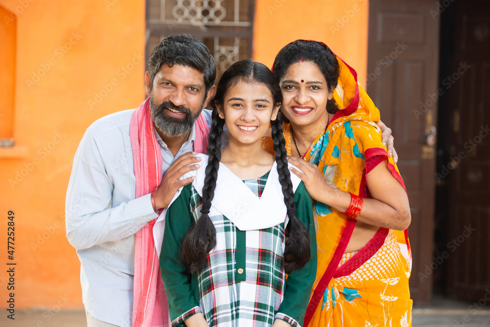 Portrait of happy Indian family standing outside their house in village ...