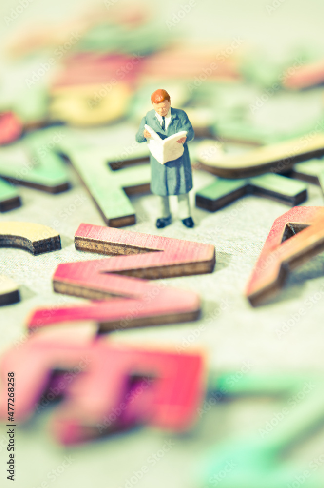 miniature figruine of a man reading and alphabet letters around it ...