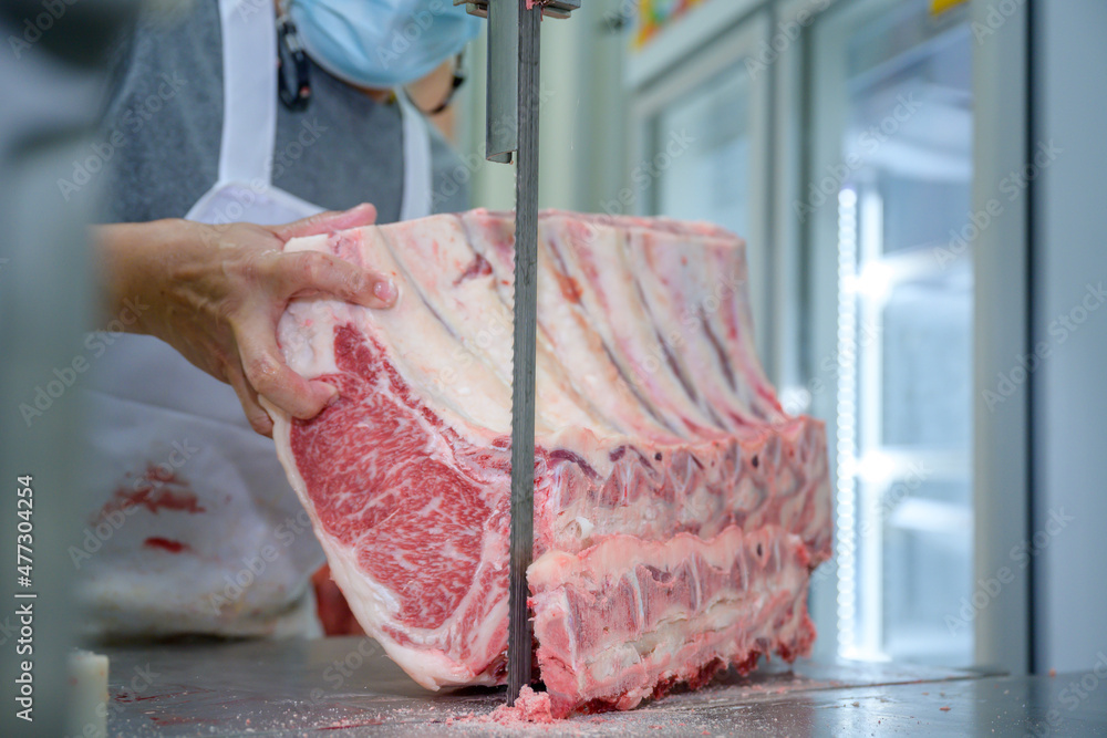 Close-up of raw meat cutting with a saw or bone cutter in an abattoir ...