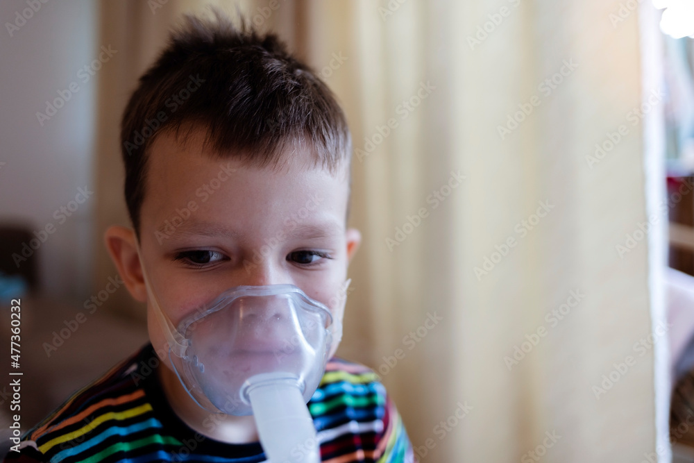Child holds a mask vapor inhaler. Sick Caucasian boy using inhaler ...