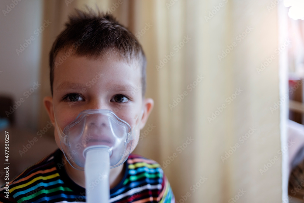 Child holds a mask vapor inhaler. Sick Caucasian boy using inhaler ...