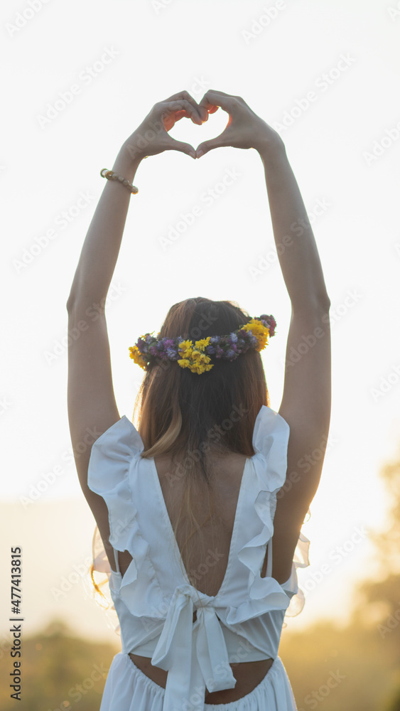 young woman puts a heart-shaped hand over her head to symbolize ...