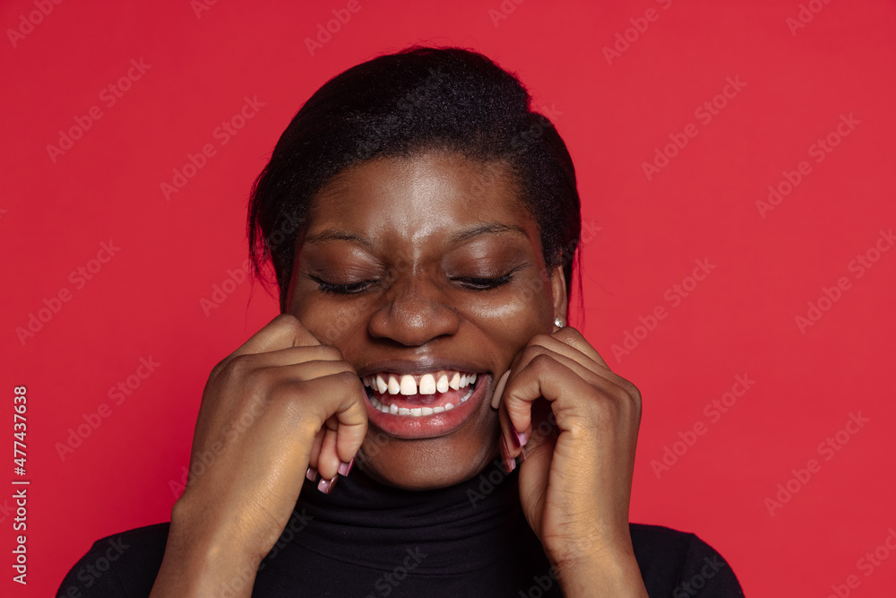 Portrait of young dark skinned girl laughing isolated on dark red ...