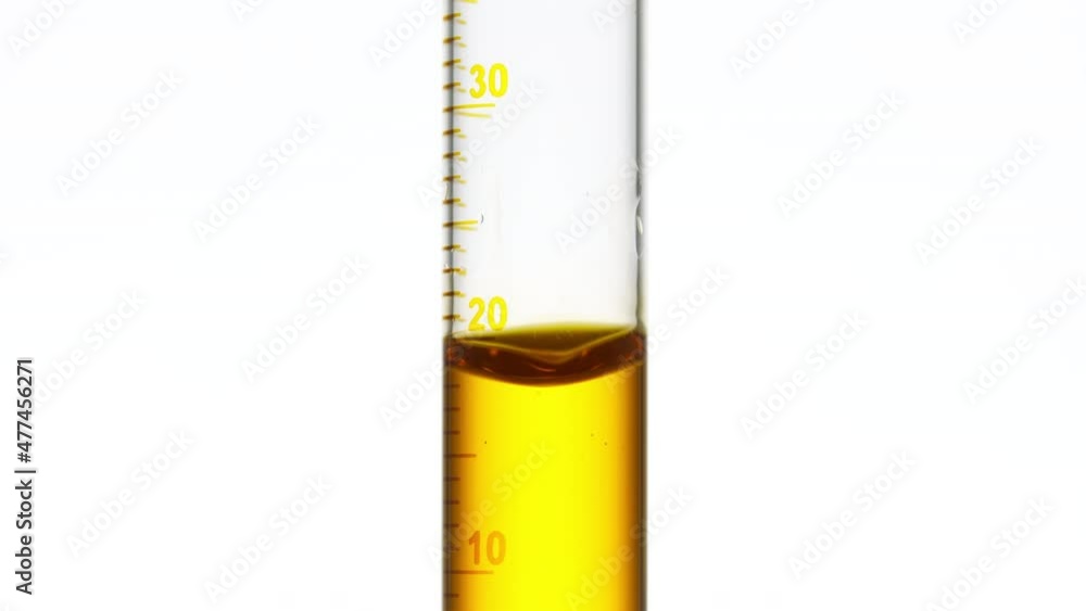 Vidéo Stock Drop of yellow fluid is falling down into graduated ...