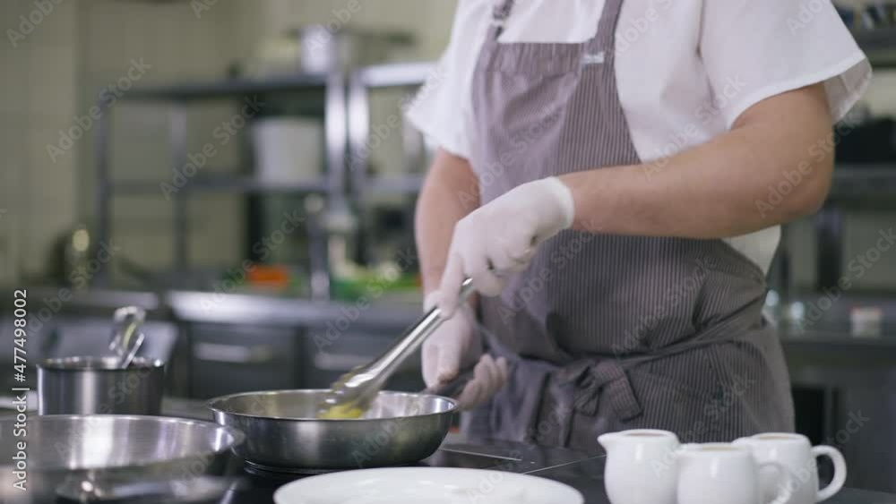 Unrecognizable cook in apron turning pineapple frying fruit slice on ...