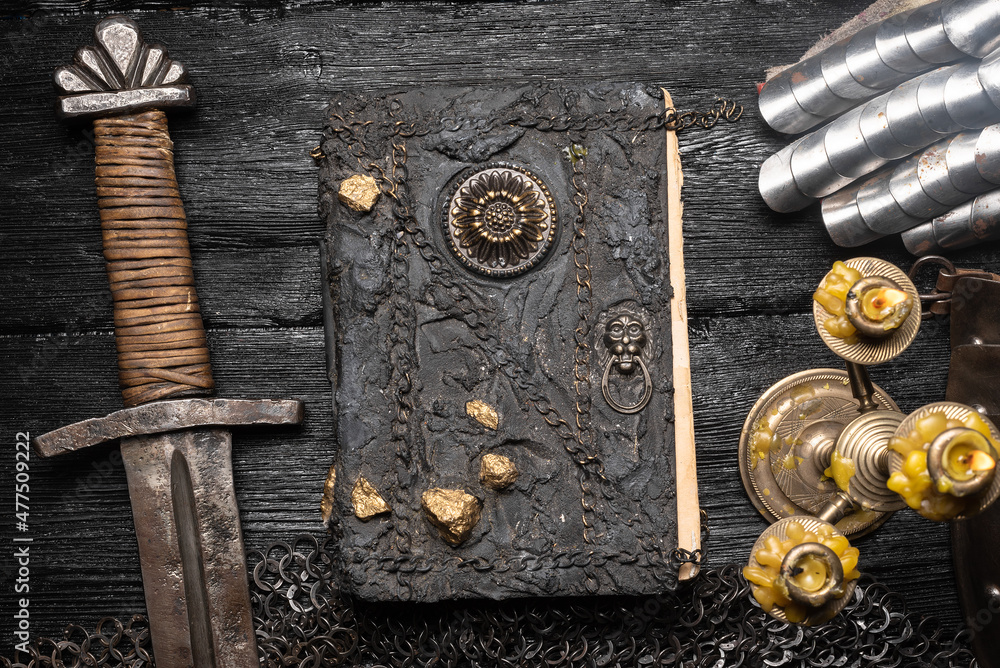 Ancient story book and knight sword on the old wooden table background ...