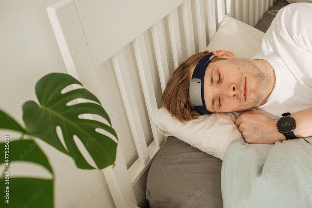 Man sleeping on bed with smart sleep headband. Smart sleep tracker ...
