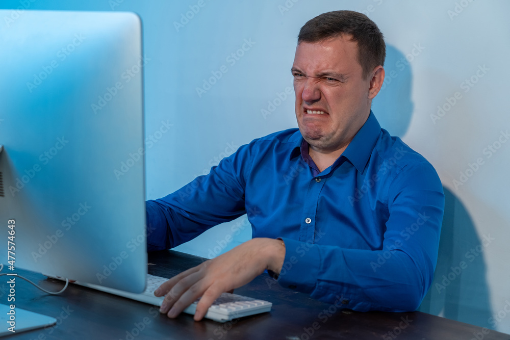 Millennial man looking disgusted in front of his computer in office ...