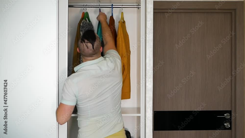 Soft focus Young man tries on clothes nervously, get clothes out of the ...