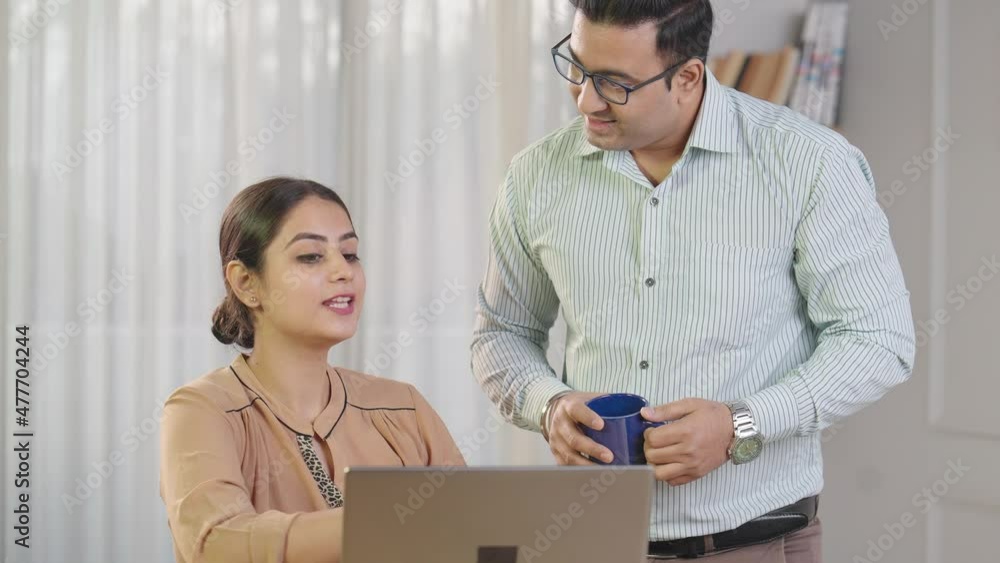 Young Indian Asian male senior corporate employee assisting his junior ...