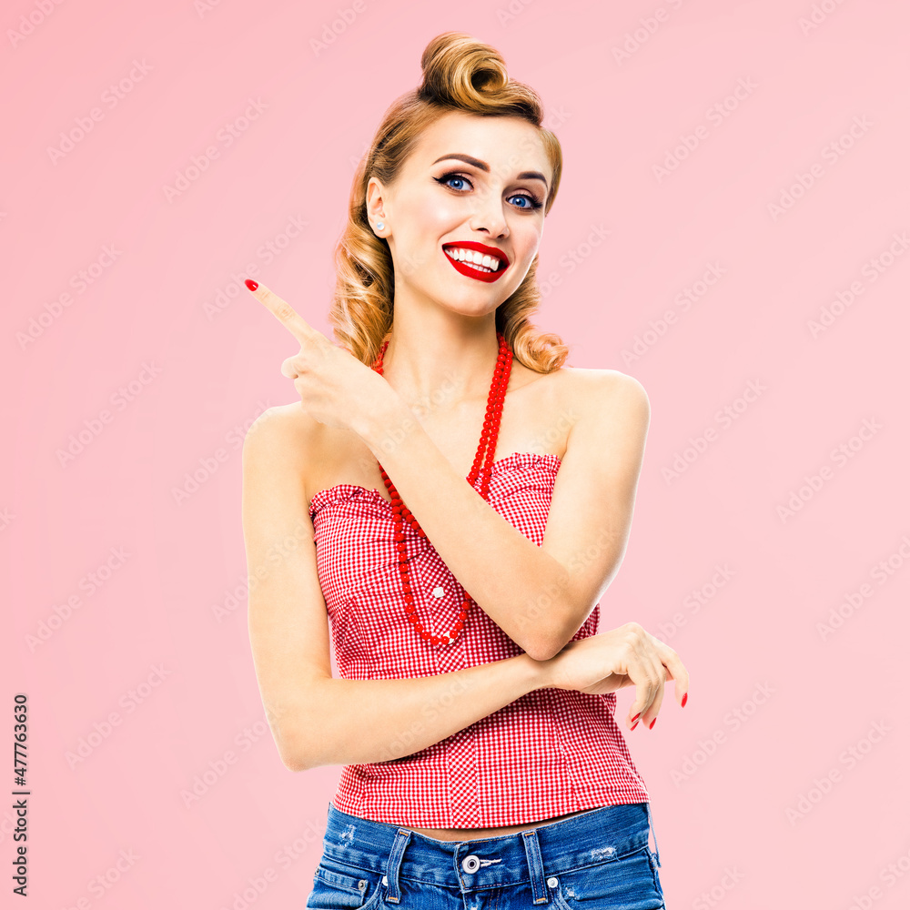 Happy smiling blonde woman pointing at something. Excited girl in pin ...