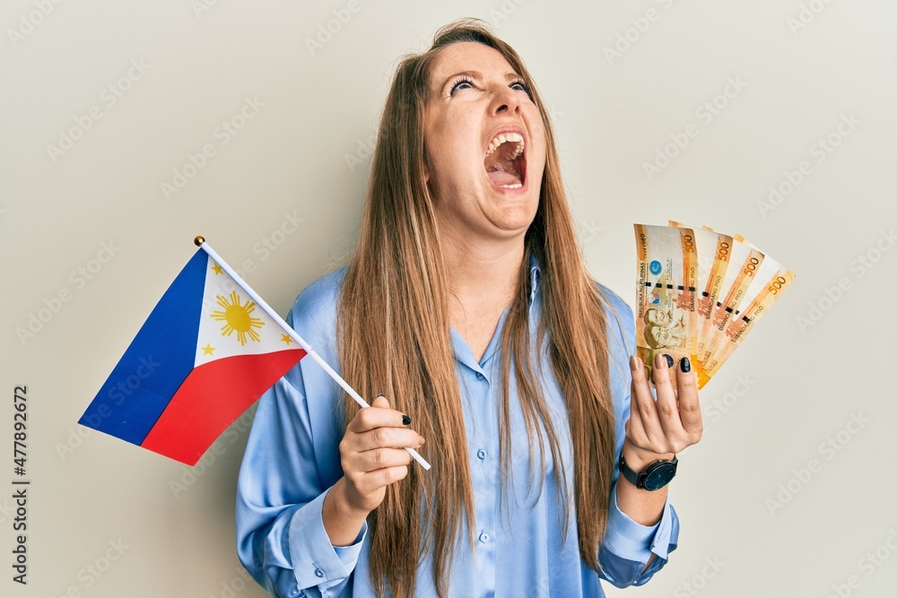 Young blonde woman holding philippine flag and philippines pesos ...