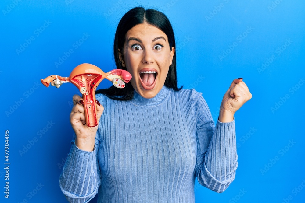 Beautiful brunette woman holding anatomical model of female genital ...