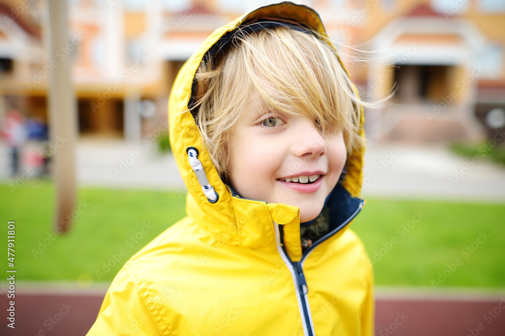 Cheerful little boy in yellow jacket is enjoying of walking on spring ...