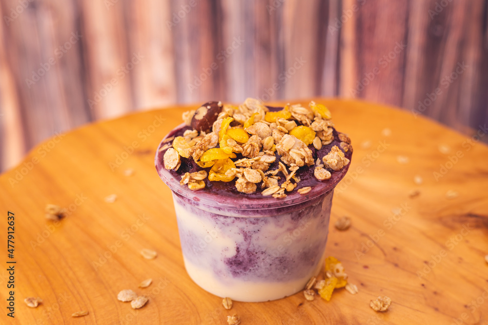 Açaí. Um açaí congelado com leite condensado e granola em um pote de ...