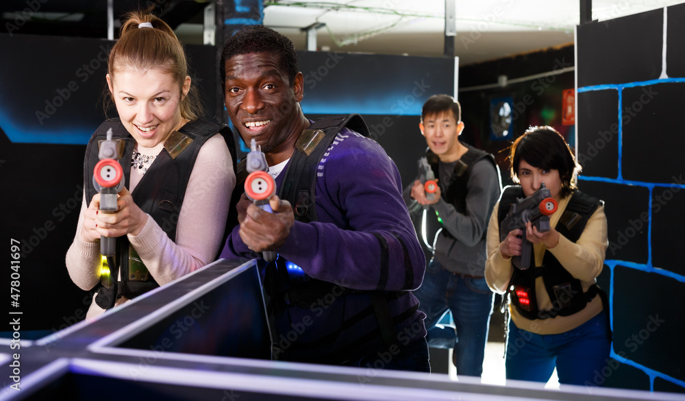 Fine laser tag players of different nationalities aiming laser guns at ...