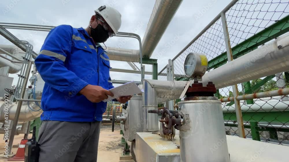 Petroleum refinery production technicians inspect pressure gauge ...