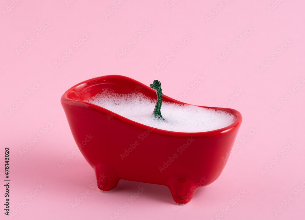 Spa and Hygiene concept . Dinosaur bathe in a small tub full of foam on ...