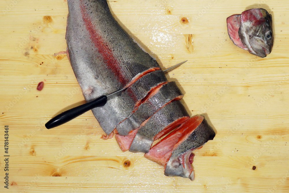 On the table, on a cutting board, lies a gutted fish from the salmon ...