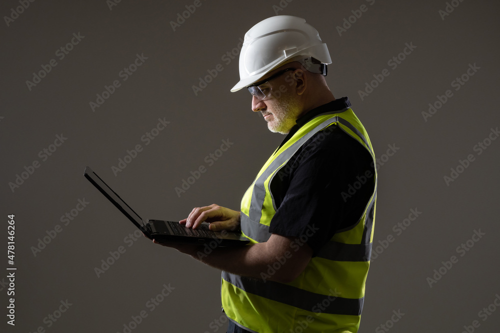 Builder laptop. Adult builder man with a laptop in his hands. Portrait ...