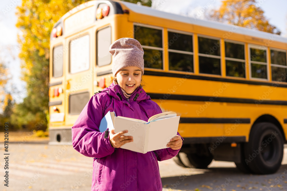 Little girl standing by a big school bus with her books. Stock Photo ...