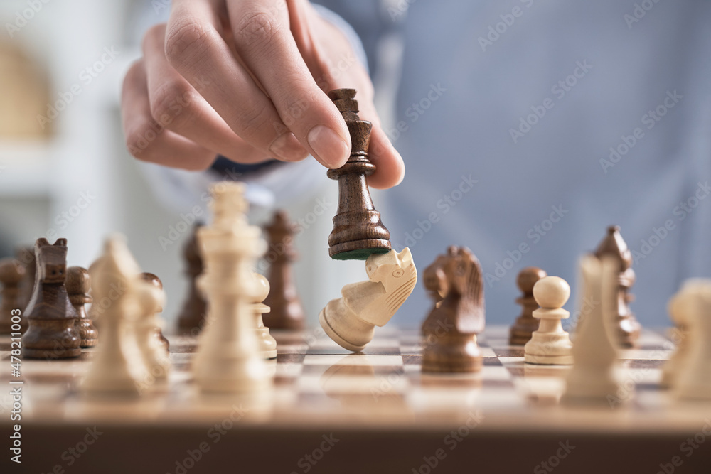 Man's hand holds a chess piece king. A dark colored chess piece. The ...