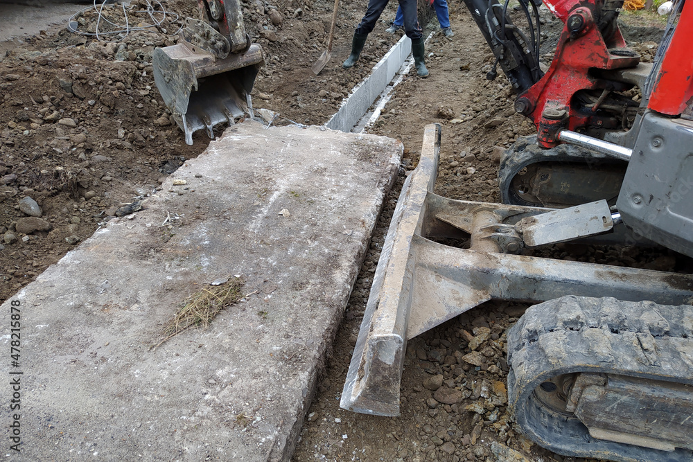 The excavator puts concrete slabs for moving through the gutter ...