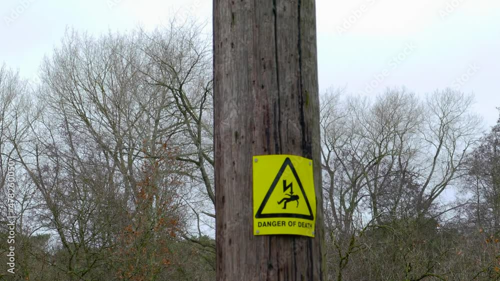 Tilt shot revealing a bright yellow warning sign mounted on a wooden ...