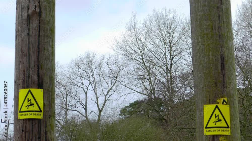 An establishing shot of high voltage warning signs mounted on wooden ...