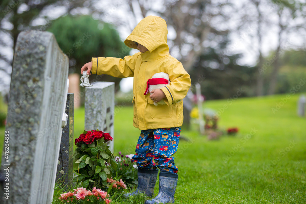 Sad little child, blond boy, standing in the rain on cemetery, sad ...
