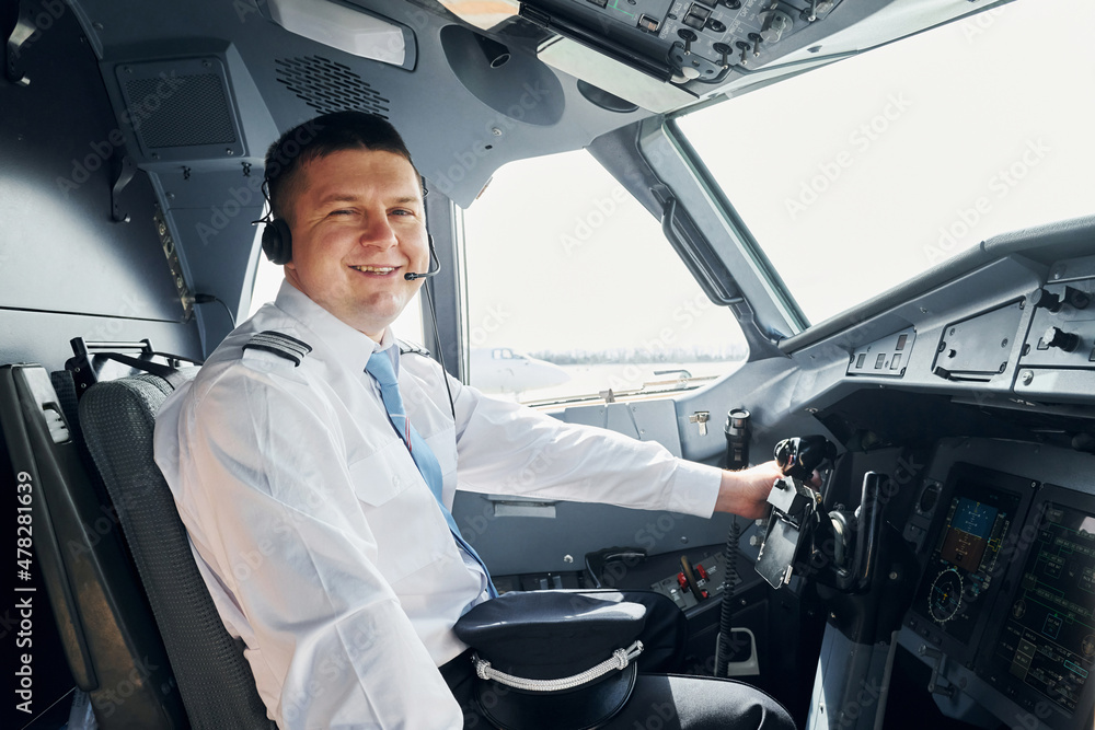 Side view. Pilot in formal wear sits in the cockpit and controls ...