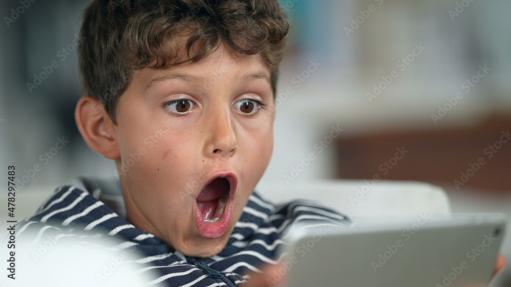 Child excited reaction playing video-game. Boy shocking surprise open ...