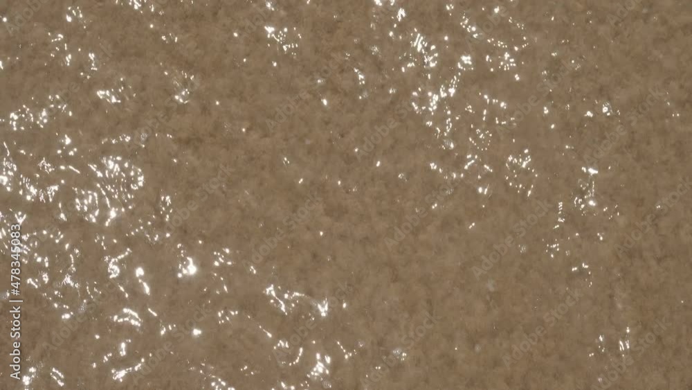 Sea water flush down and absorb in soft sand, top down close up shot of ...