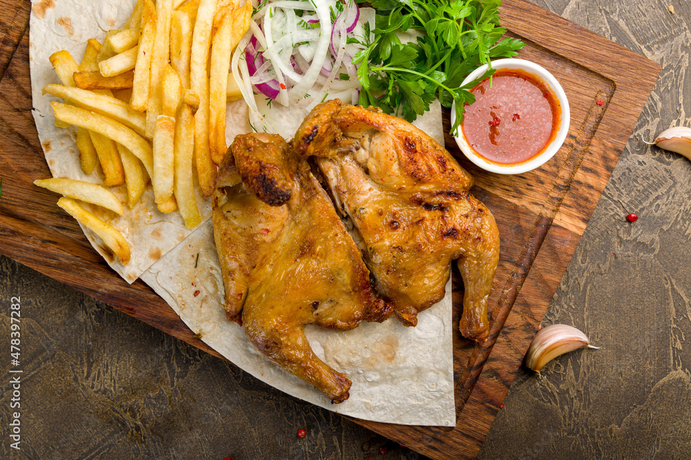fried chicken tobacco on the board with french fries, red onion and ...