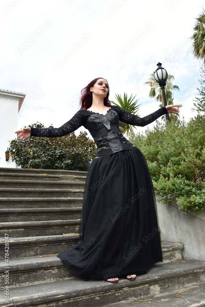 portrait of pretty female model with red hair wearing glamorous gothic ...